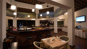 Um restaurante com teto alto, área de bar e espaço de refeições com mesas e cadeiras.