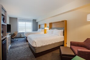 Quarto de hotel com duas camas, uma escrivaninha, uma cadeira, televisão e vista para a cidade.