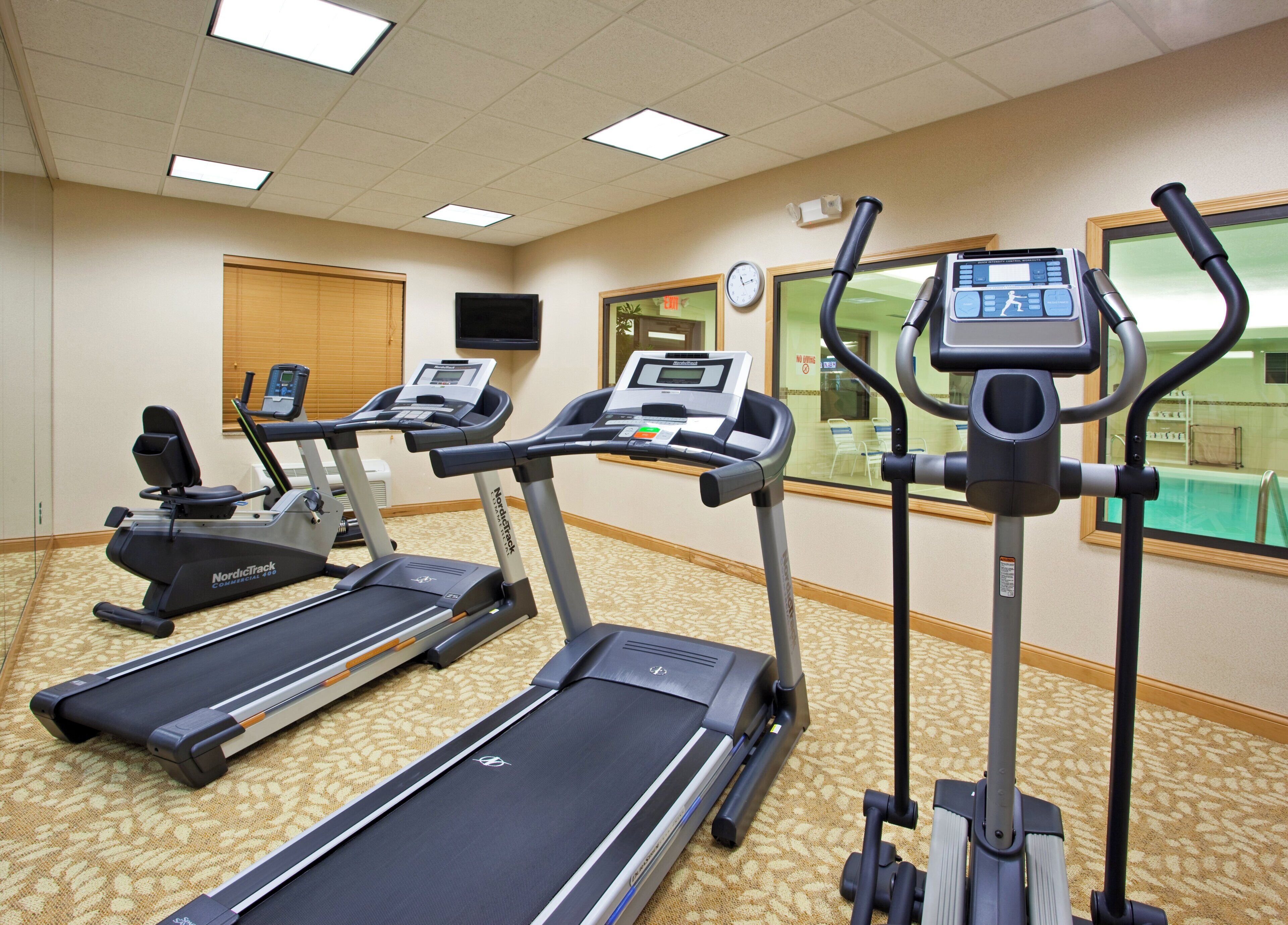 Sala de ginástica com esteiras, bicicleta ergométrica e máquina de remo.