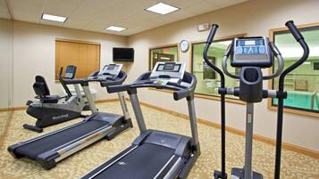 Sala de ginástica com esteiras, bicicleta ergométrica e máquina de remo.
