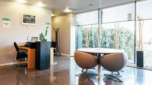 Um espaço de escritório moderno com balcão de recepção, computador e área de estar com duas cadeiras.