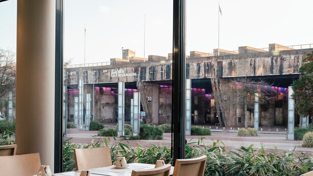 Um restaurante com vista para um edifício moderno com a placa “BASE SOUS-MARINE” e o número “10”.
