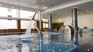 Piscina interna com vários jatos de água, piso em azulejo e design de interiores moderno.