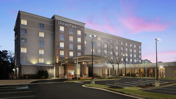 Um hotel DoubleTree by Hilton com design moderno, entrada coberta e estacionamento.