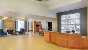 Um hall amplo com balcão de recepção, área de estar e parede com exibição em nuvem de palavras.