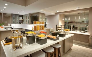 Uma cozinha moderna com bancada de mármore, diversos pontos de preparo de alimentos e uma máquina de café.