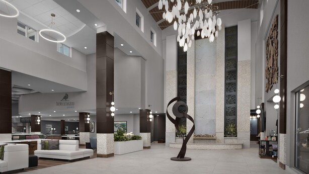 Um hall amplo com um lustre moderno, área de estar e uma grande escultura abstrata.