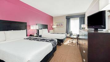 Quarto de hotel com duas camas, televisão, escrivaninha e cómoda.