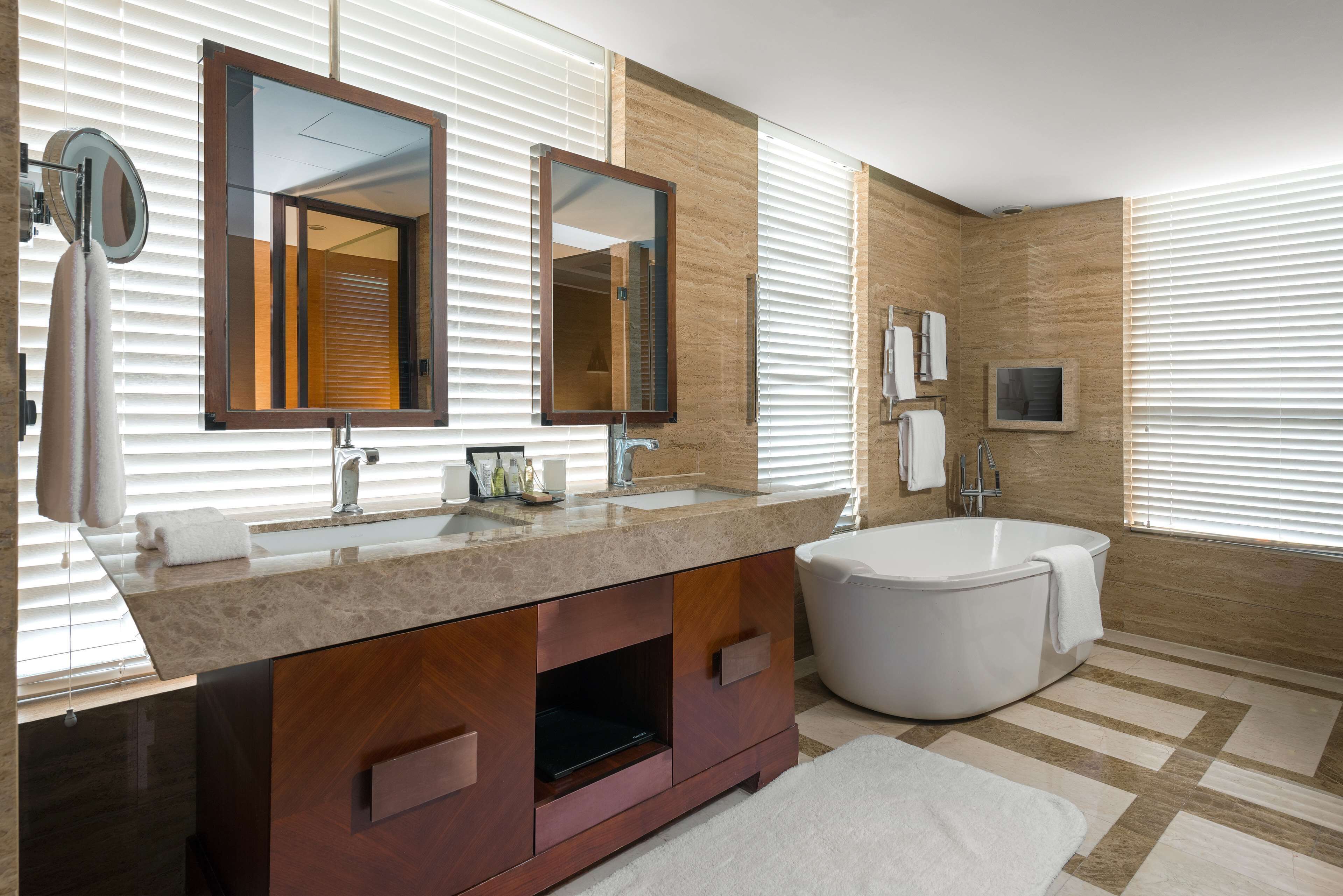 Uma casa de banho moderna com duas pias, um espelho grande, uma banheira e um lavatório com gavetas.