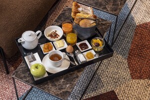 Bandeja de café da manhã com diversos alimentos e bebidas sobre uma mesa de mármore.
