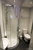 Uma casa de banho moderna com cabine de duche em vidro, sanita e lavatório.