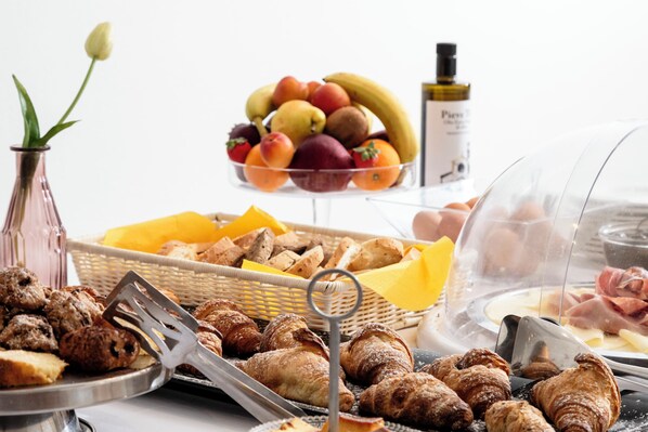 Buffet com pastelaria, frutas e uma garrafa de azeite.