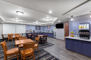 Cozinha moderna com painel azul, mesas de jantar de madeira e uma seleção de frutas.
