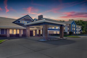 Um hotel com entrada coberta, vários andares e uma placa característica da marca American Inn.