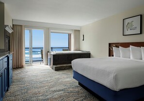 Quarto de hotel com uma cama grande, banheira e vista para o oceano.