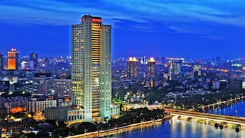 Um hotel alto com um letreiro chamativo 'Marriott', rodeado por um horizonte urbano e um rio.