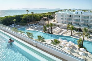 Um resort com uma piscina grande, espreguiçadeiras e vista para o mar.