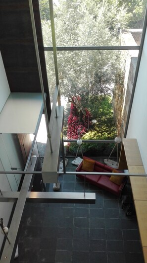 Um interior moderno com vista para um jardim através de grandes janelas.
