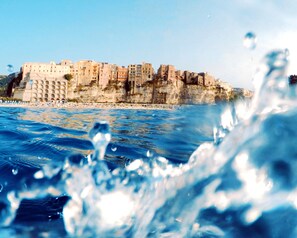 Paisagem costeira com edifícios históricos e vista clara para o mar.