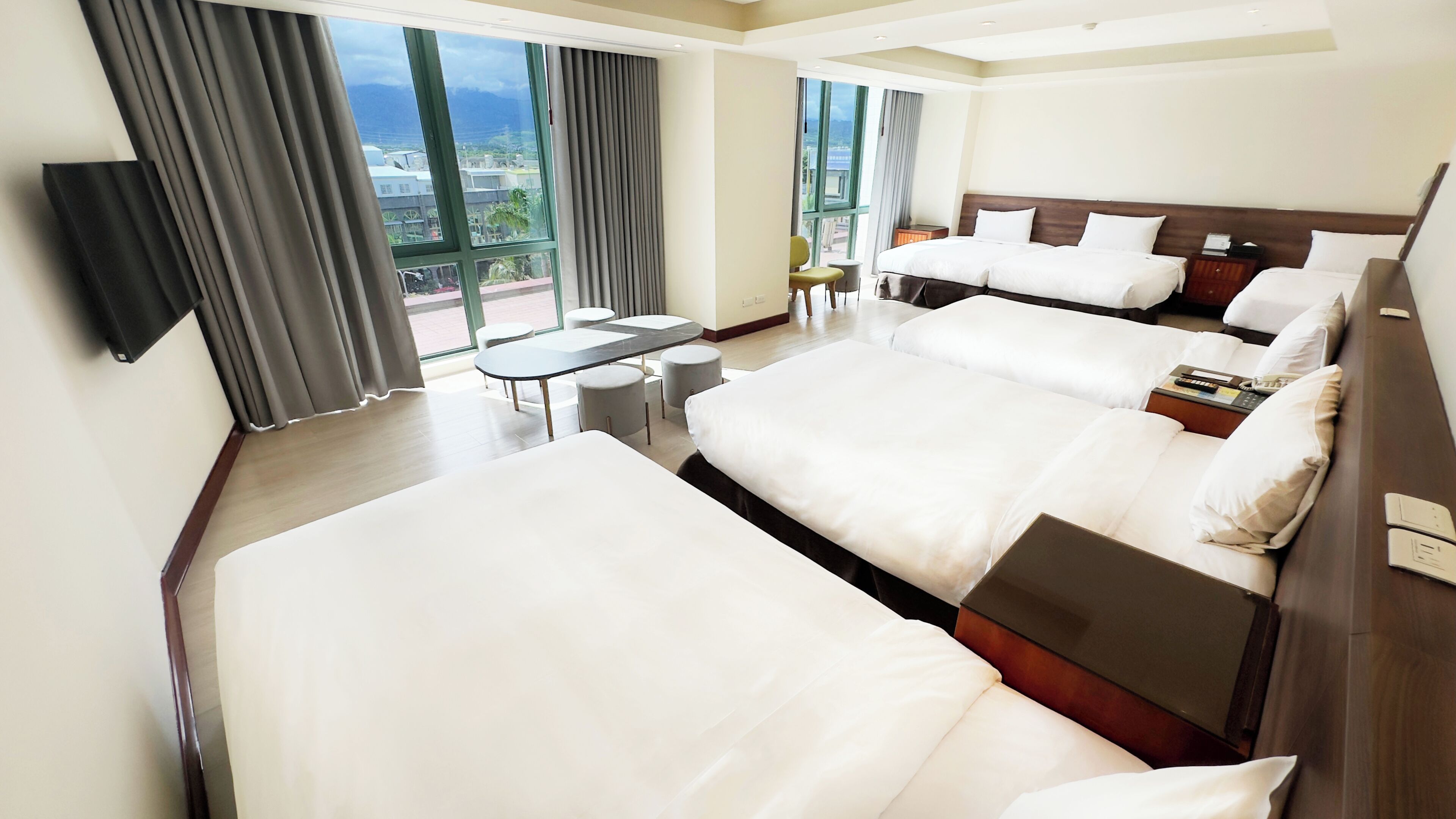 Quarto de hotel com duas camas, uma mesa pequena, uma cadeira e uma televisão.
