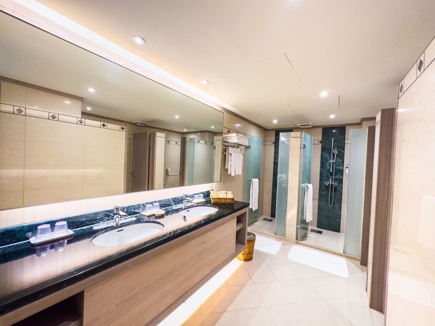 Uma casa de banho moderna com um espelho grande, duas pias, um chuveiro e um espaço para toucador.