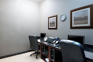Uma sala de conferência com uma mesa, cadeiras, um relógio e quadros na parede.