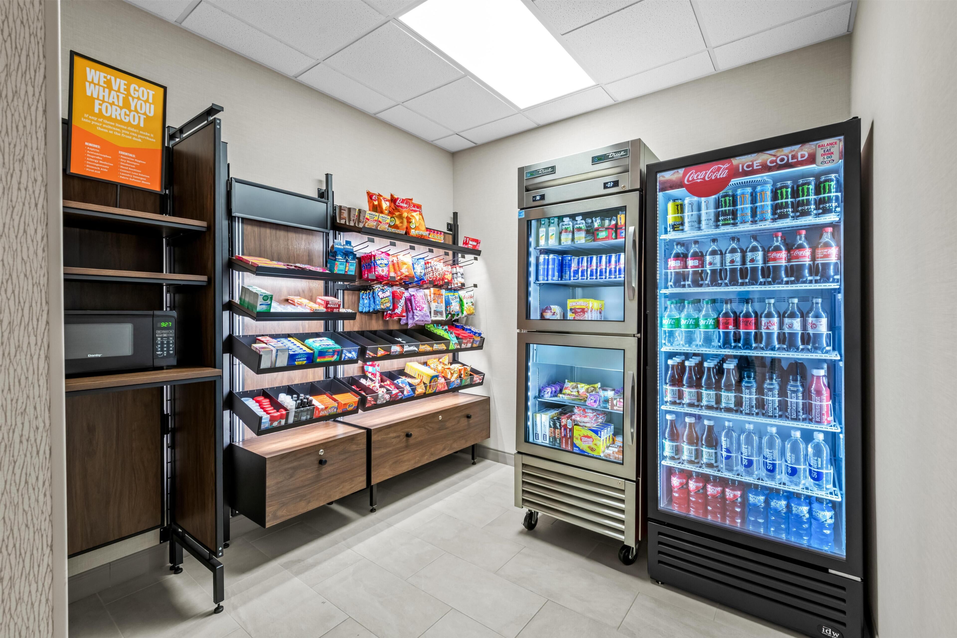 Espaço com máquinas de venda automática de lanches, micro-ondas e refrigerador de Coca-Cola.