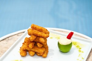 Um prato com alimentos empanados e uma tigela verde com um objeto vermelho.