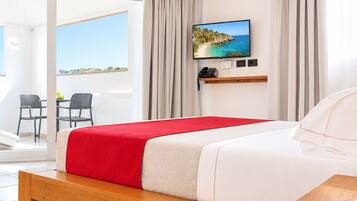 Quarto de hotel com cama, mesa de cabeceira, televisão na parede e varanda com vista.