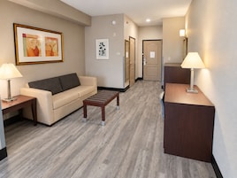 Um saguão de hotel com sofá, mesa de centro, escrivaninha e balcão de recepção.