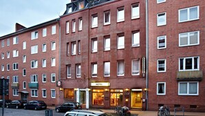 Um hotel de tijolos vermelhos com vários andares, janelas amplas e uma entrada visível.