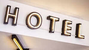 Letras iluminadas formando a palavra 'HOTEL' numa parede.