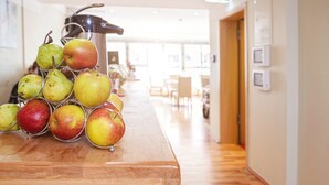 Exposição de frutas com maçãs e peras sobre um balcão de madeira no saguão de um hotel.