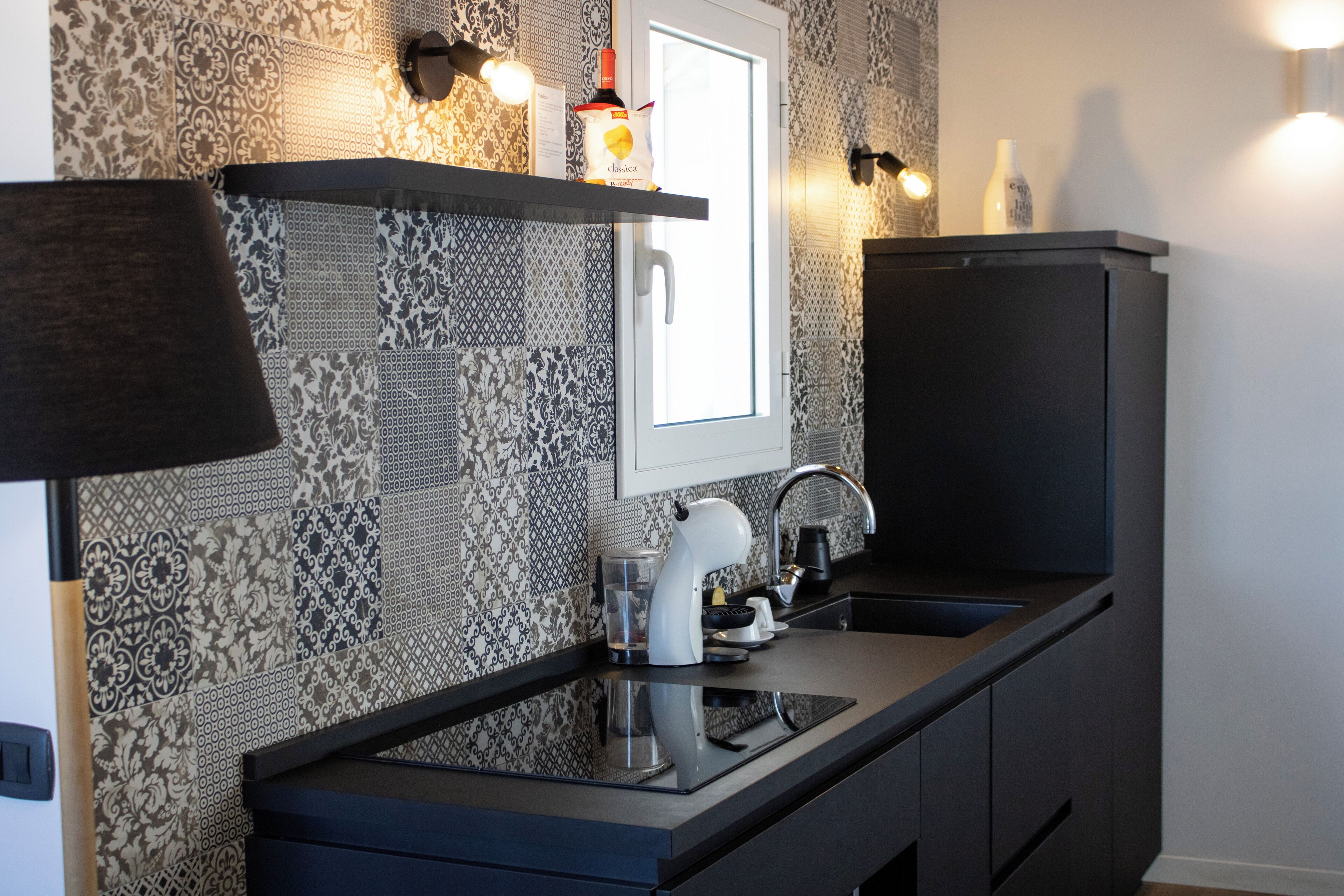 Uma cozinha com painel decorativo, máquina de café e armário preto.