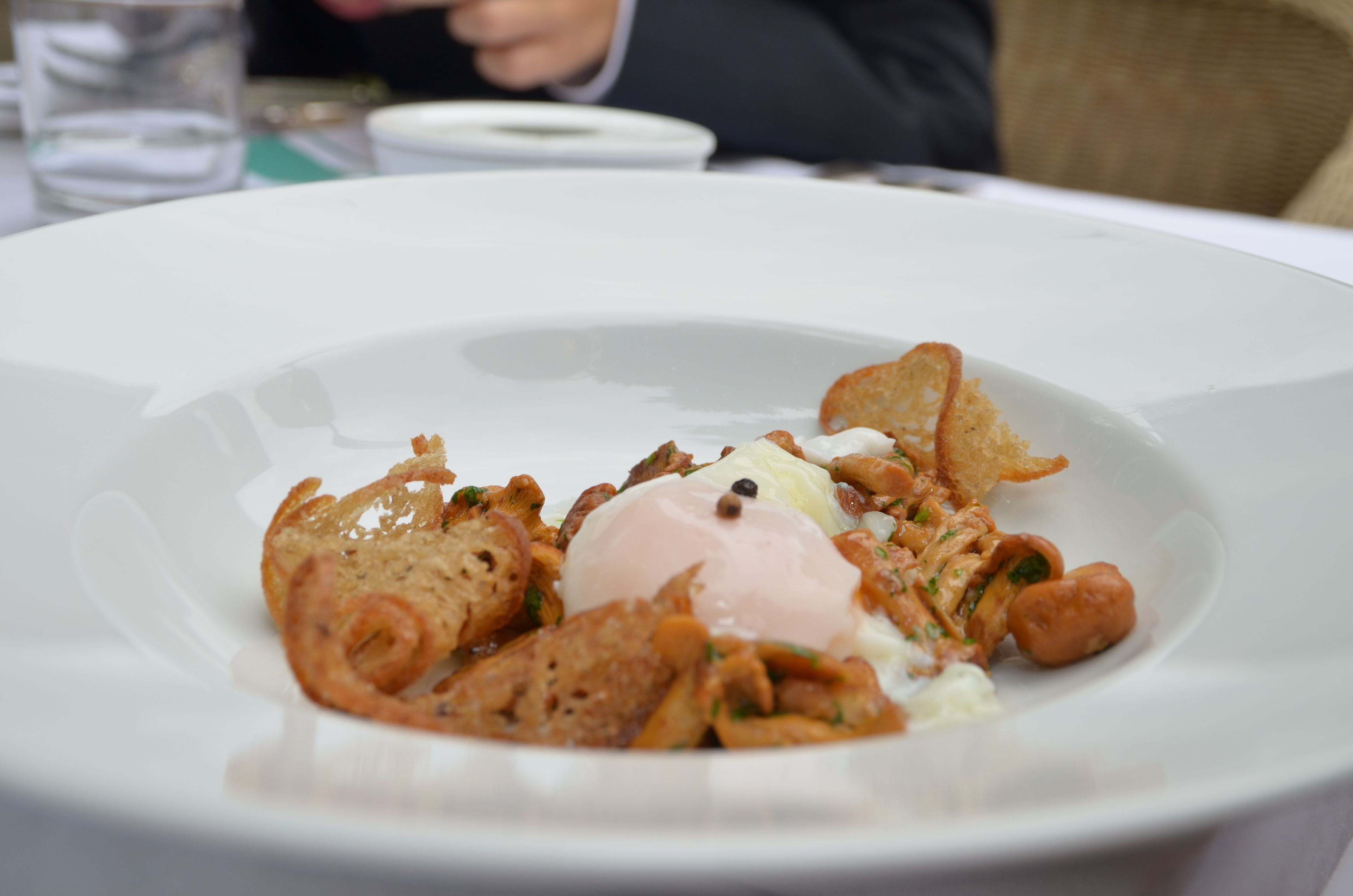 Um prato branco com um alimento frito e um ovo cozido em água.