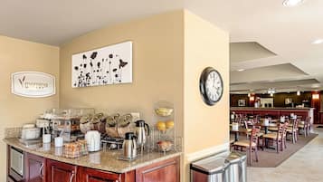 Um balcão de café da manhã com máquinas de café, uma cesta de frutas e uma placa com a inscrição 'Morning Mittley'.