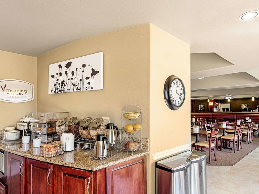 Um balcão de café da manhã com máquinas de café, uma cesta de frutas e uma placa com a inscrição 'Morning Mittley'.