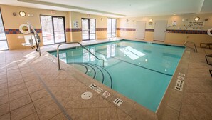 Uma piscina interior com água cristalina, linhas de profundidade marcadas e sinalização de segurança.