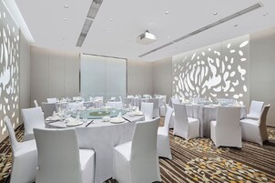 Uma sala de conferência com mesas redondas, cadeiras brancas e um design de parede estampado.