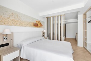 Quarto moderno com cama, mesas de cabeceira, abajur fixado na parede e uma grande obra de arte.