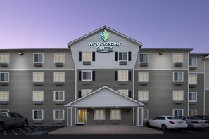 Um hotel com vários andares, entrada central e estacionamento.