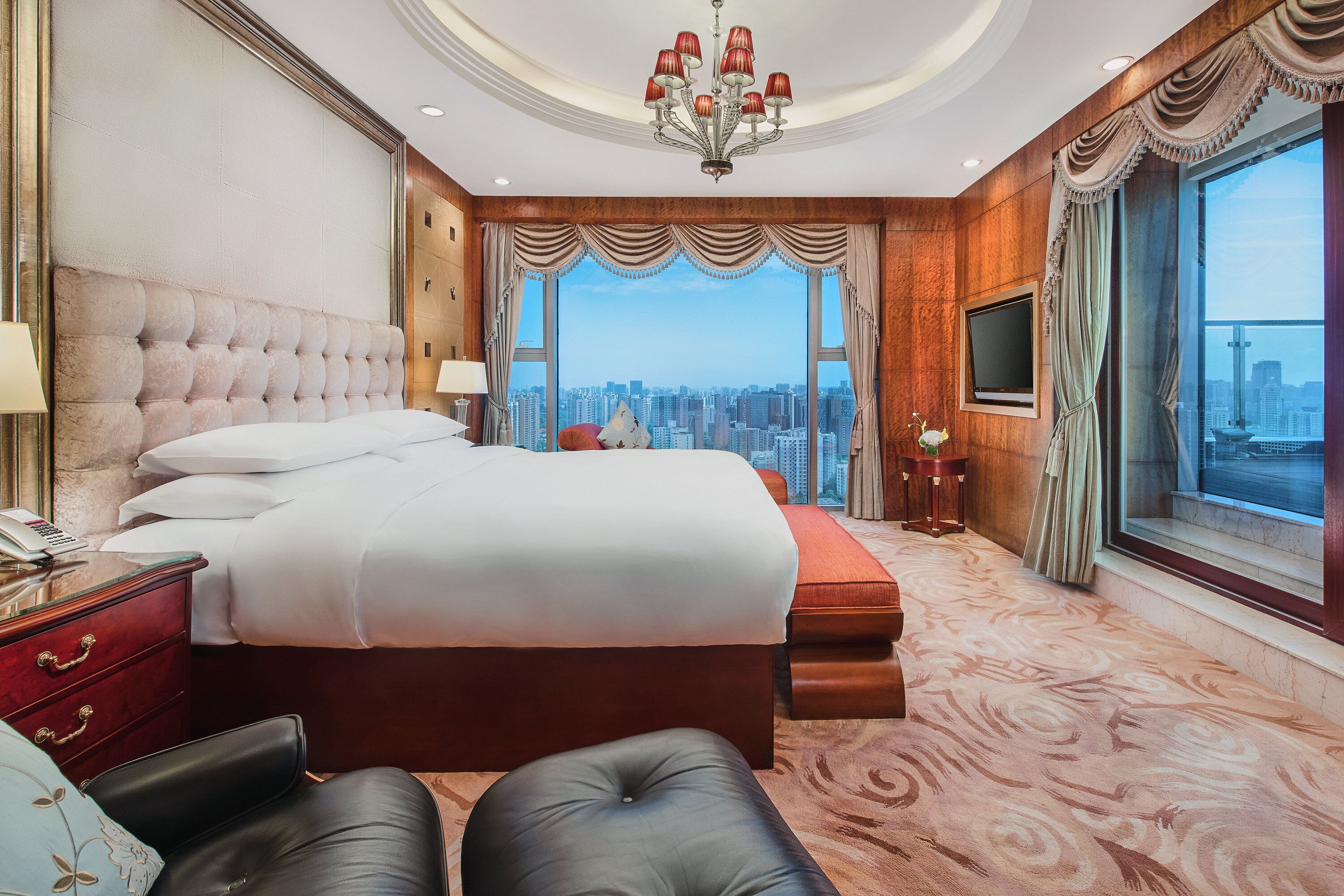 Quarto de hotel espaçoso com uma cama grande, um espaço para sentar e vista para a cidade.