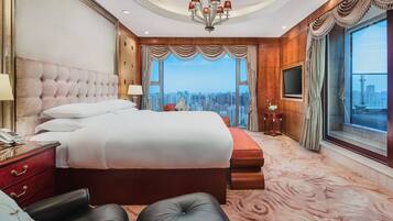 Quarto de hotel espaçoso com uma cama grande, um espaço para sentar e vista para a cidade.