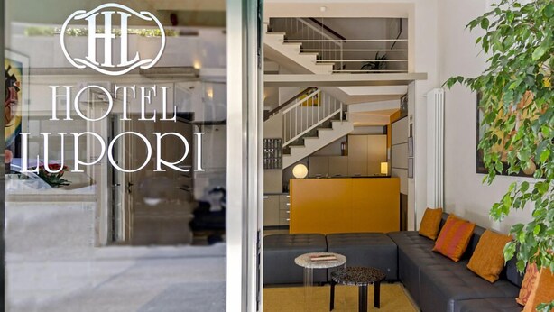 Interior moderno de hotel com escada, sofá e mesa pequena.
