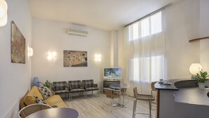 Uma sala de estar moderna com sofá, cadeiras, uma mesa de jantar e uma televisão.