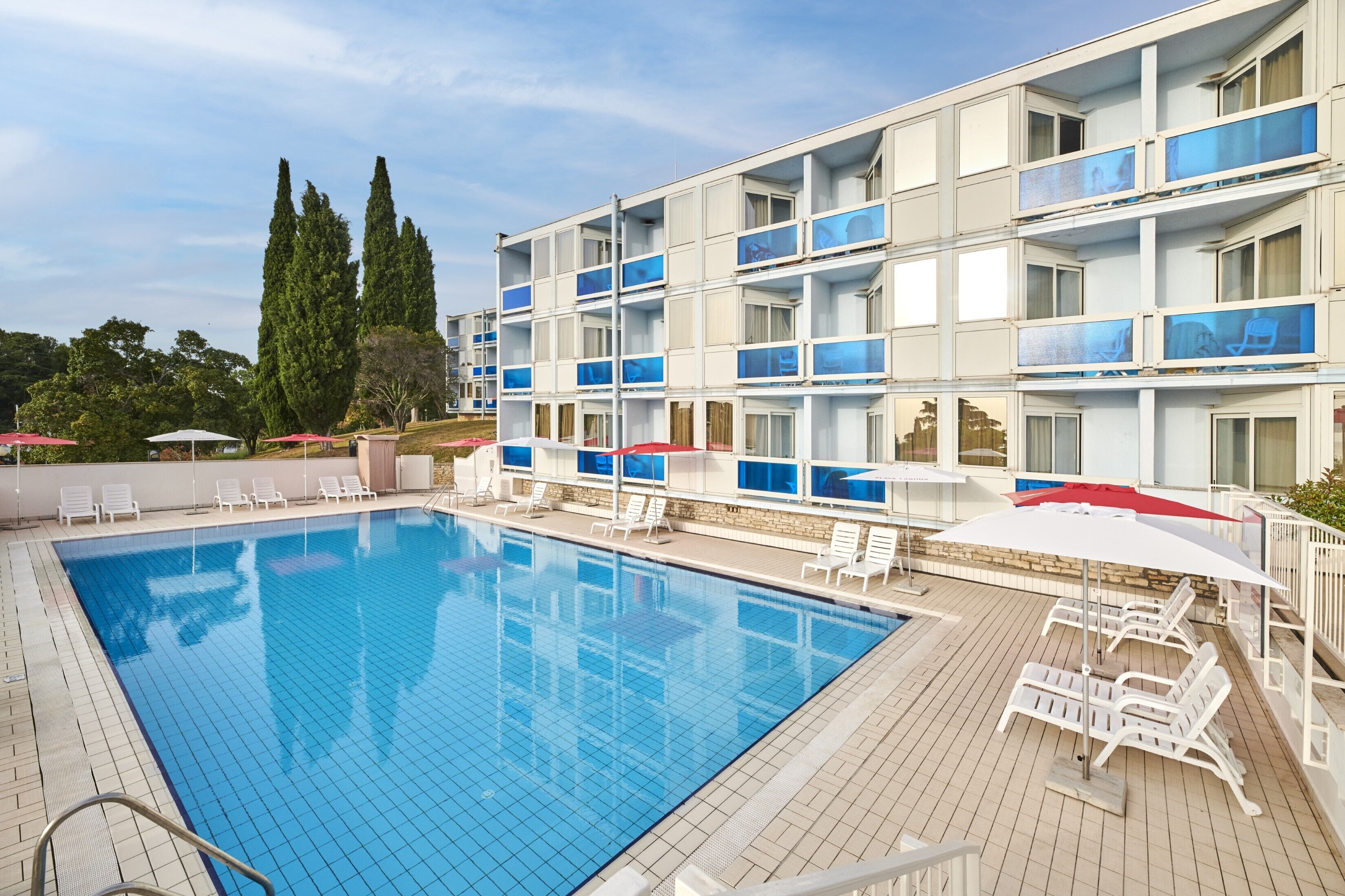Hotel com piscina, várias varandas e áreas de estar ao ar livre.
