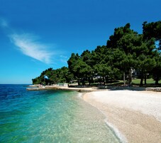 Na praia, guarda-sóis, toalhas de praia, prática de vôlei de praia 