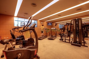 Uma academia com esteiras, elípticos e equipamentos de musculação.