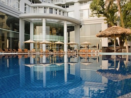 Um hotel moderno com uma grande piscina interior, cadeiras de espreguiçadeira e guarda-sóis.