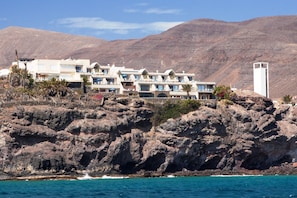 Um hotel costeiro com vários edifícios, falésias rochosas e uma vista ampla do mar.